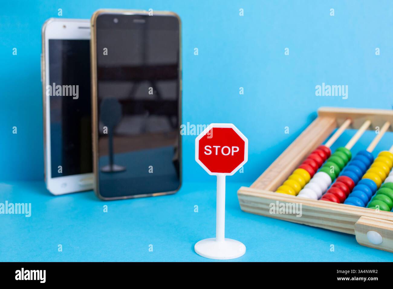 Road stop sign with defocused smartphones and abacus on blue background, digital screens and ...