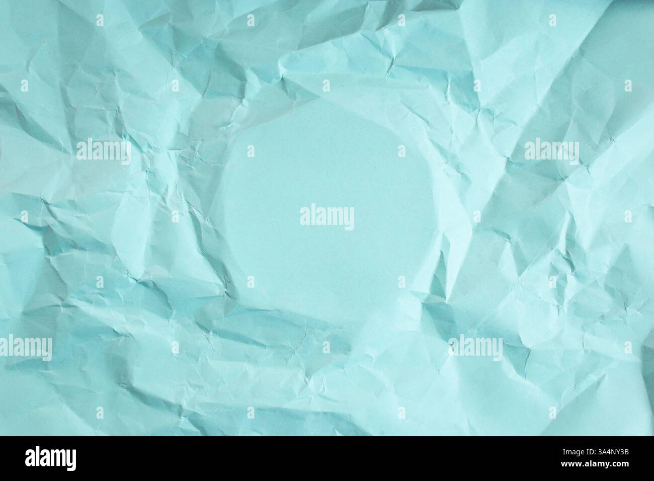 Blue crumpled paper texture with round empty copy space in the middle ...