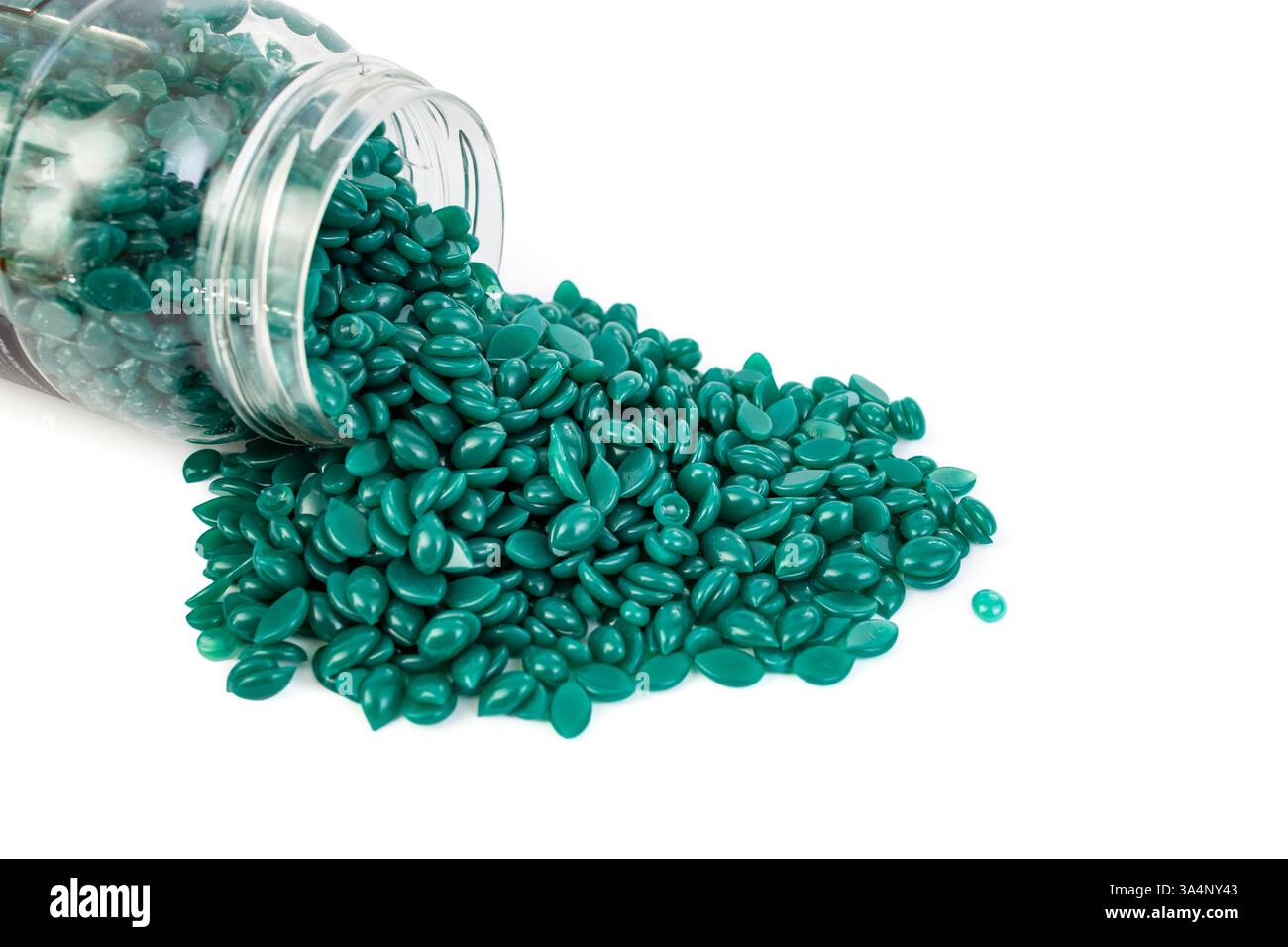 Natural epilation wax granules spilling from a plastic jar on white ...