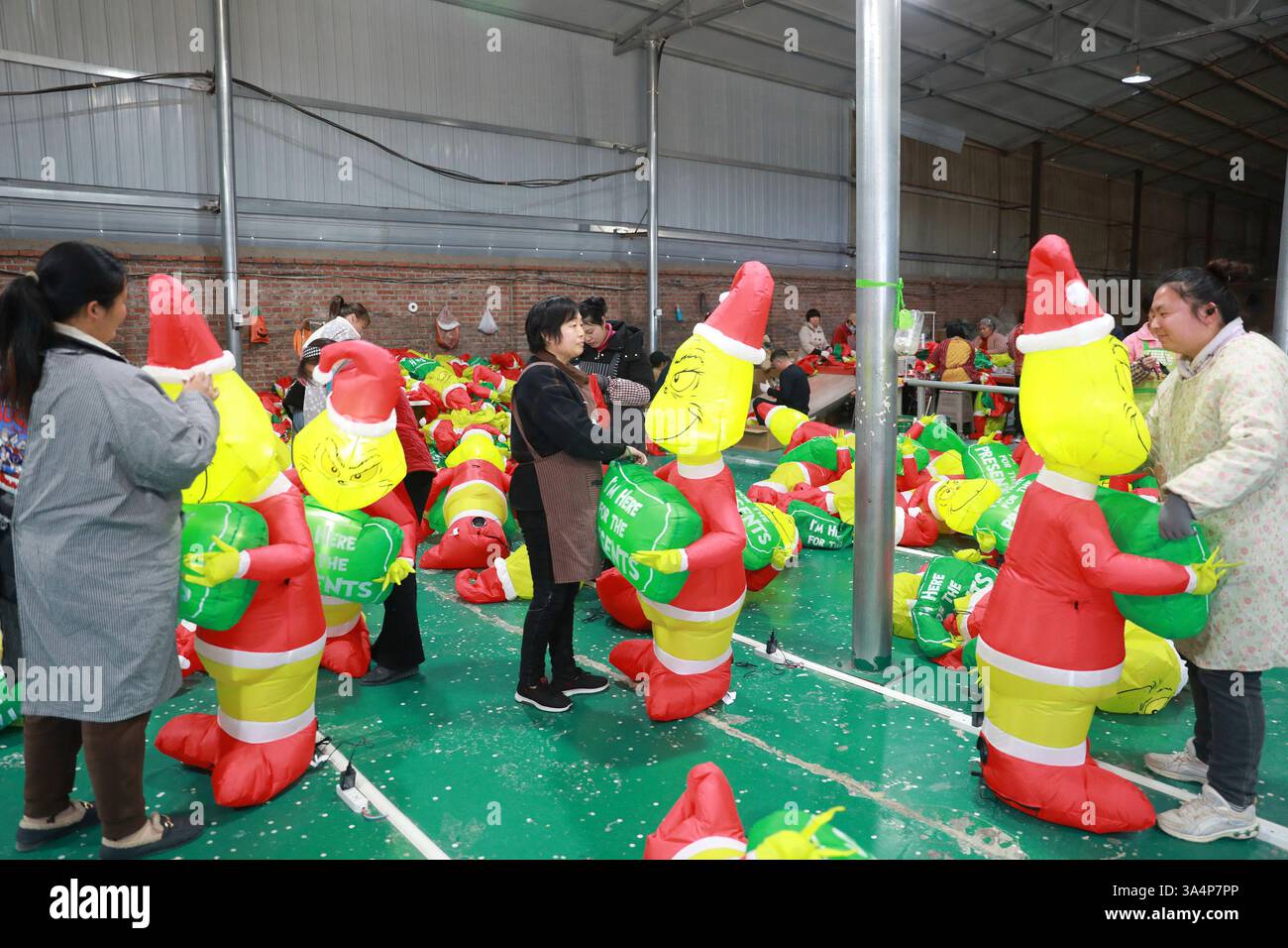 Workers check the inflated toys of The Grinch, a character created by ...