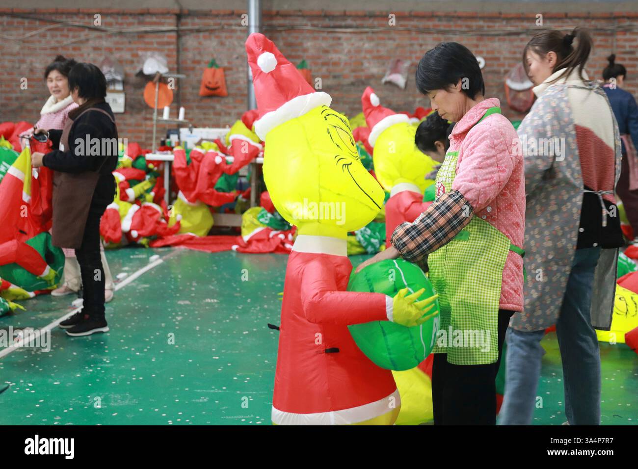 Workers check the inflated toys of The Grinch, a character created by ...