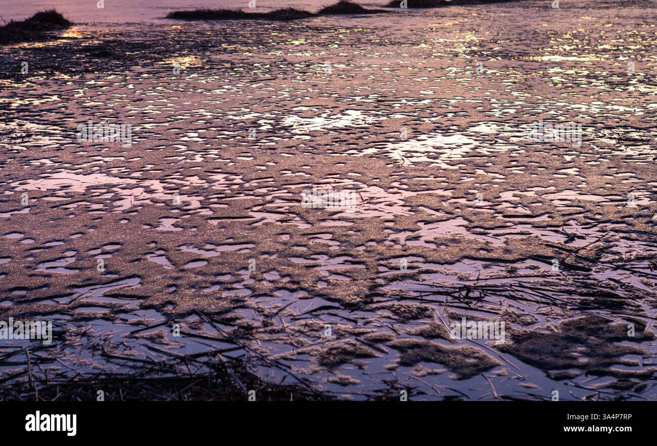 The surface of the reservoir is covered with melting ice, creating a ...