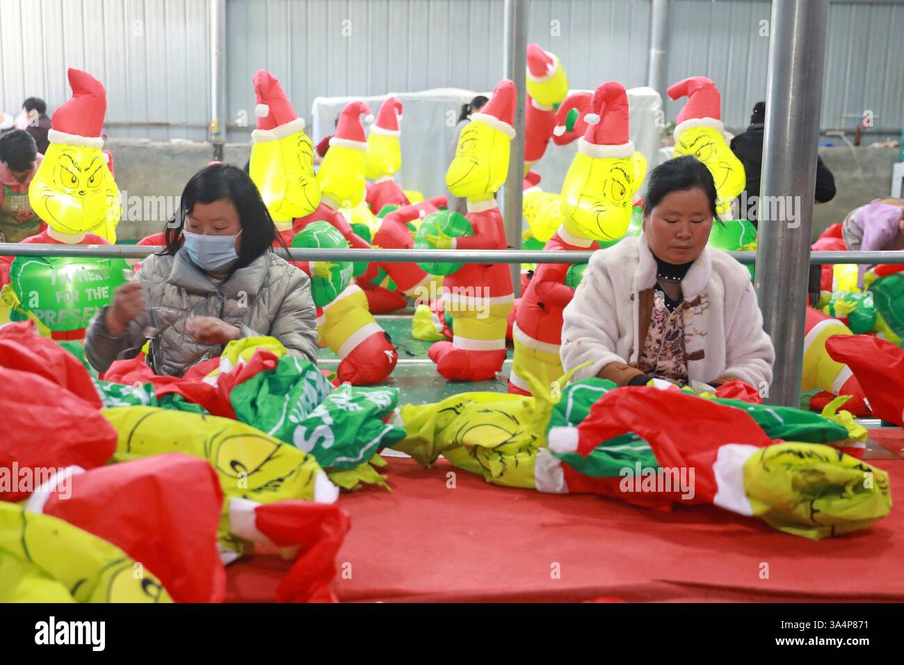 Workers check the inflated toys of The Grinch, a character created by ...