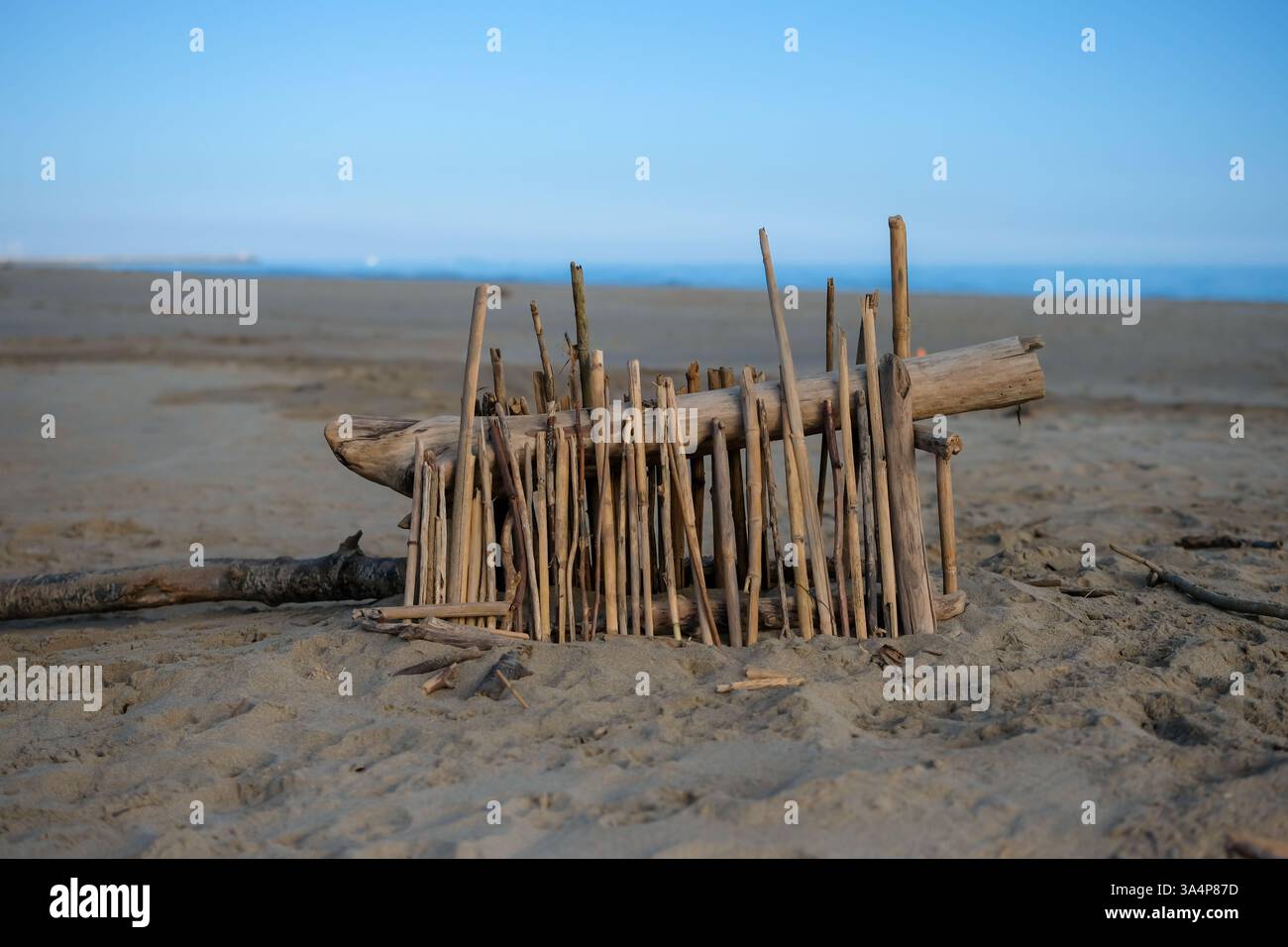 Construction of driftwood sticks placed on a sandy beach. Fine motor ...