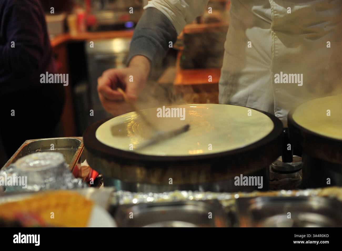 a hand of a man making a crepe in a tradicional restaurant in paris ...