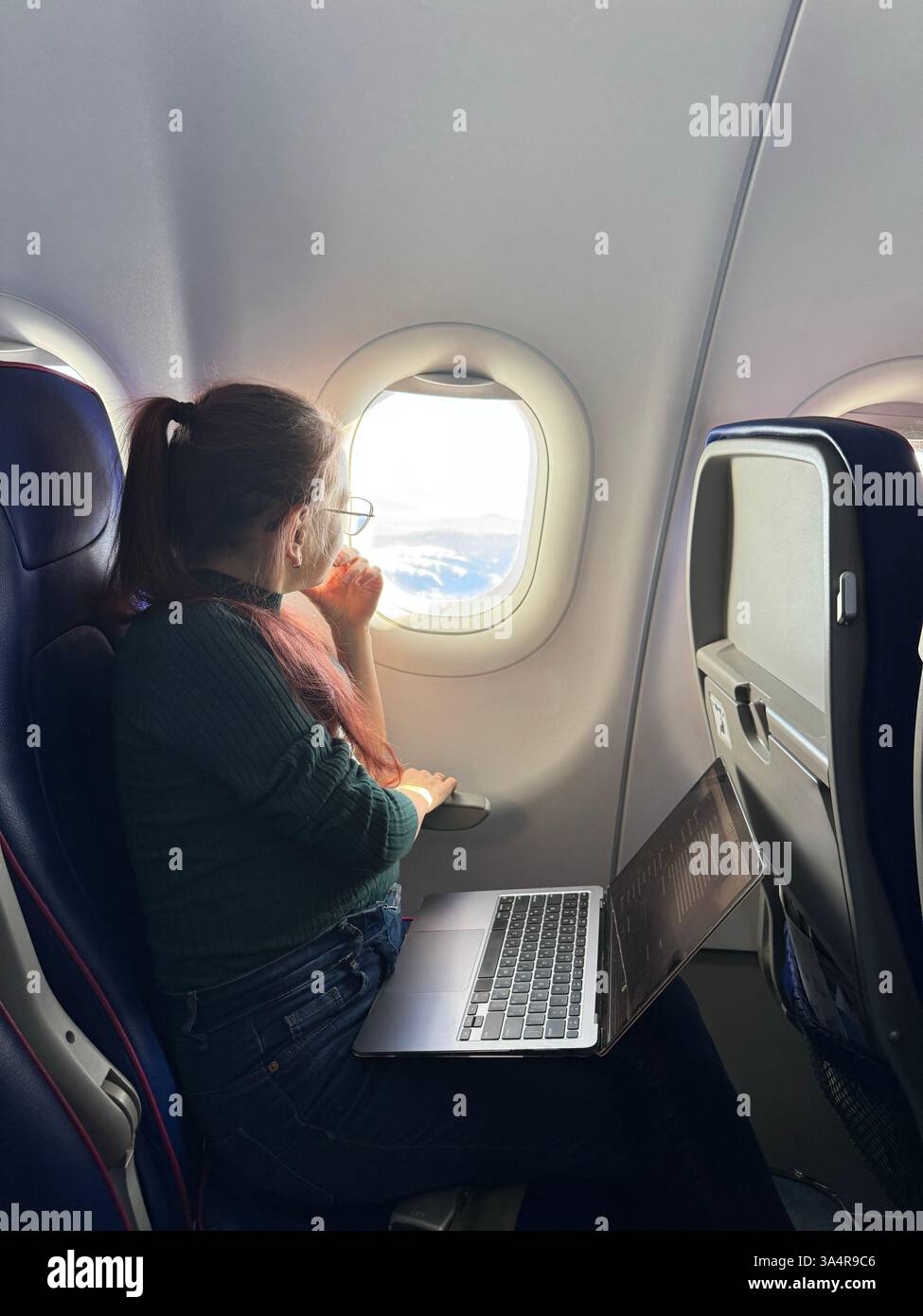 Woman Looking Out Airplane Window with Laptop on Lap Stock Photo - Alamy