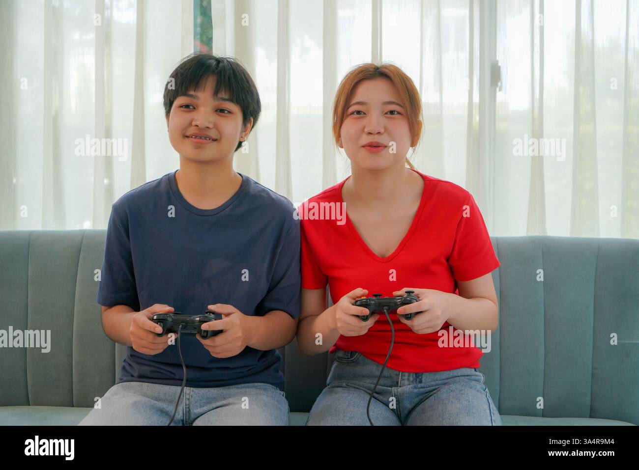 two asian friends enthusiastically gaming together, each holding a ...
