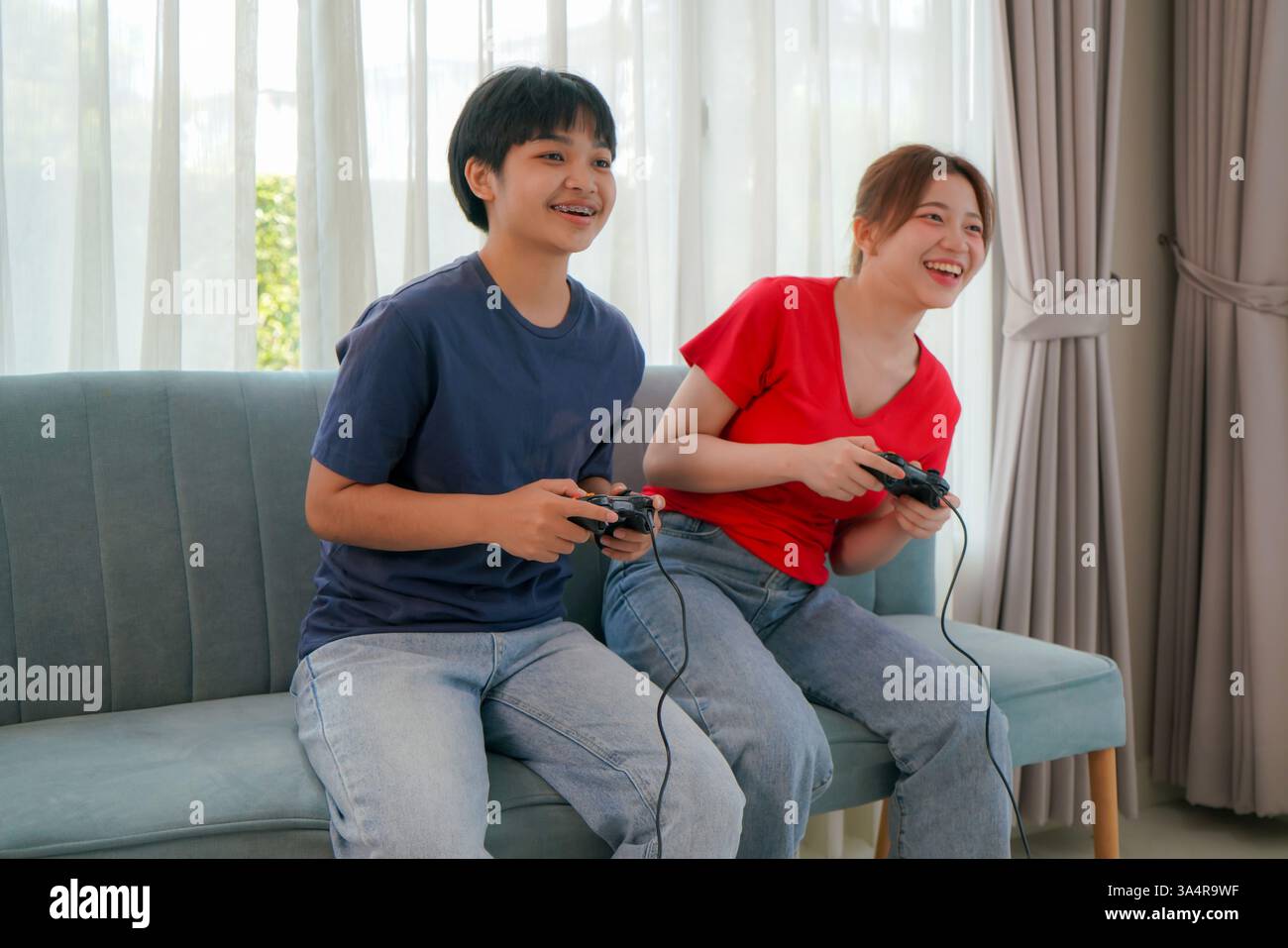 two asian friends enthusiastically gaming together, each holding a ...