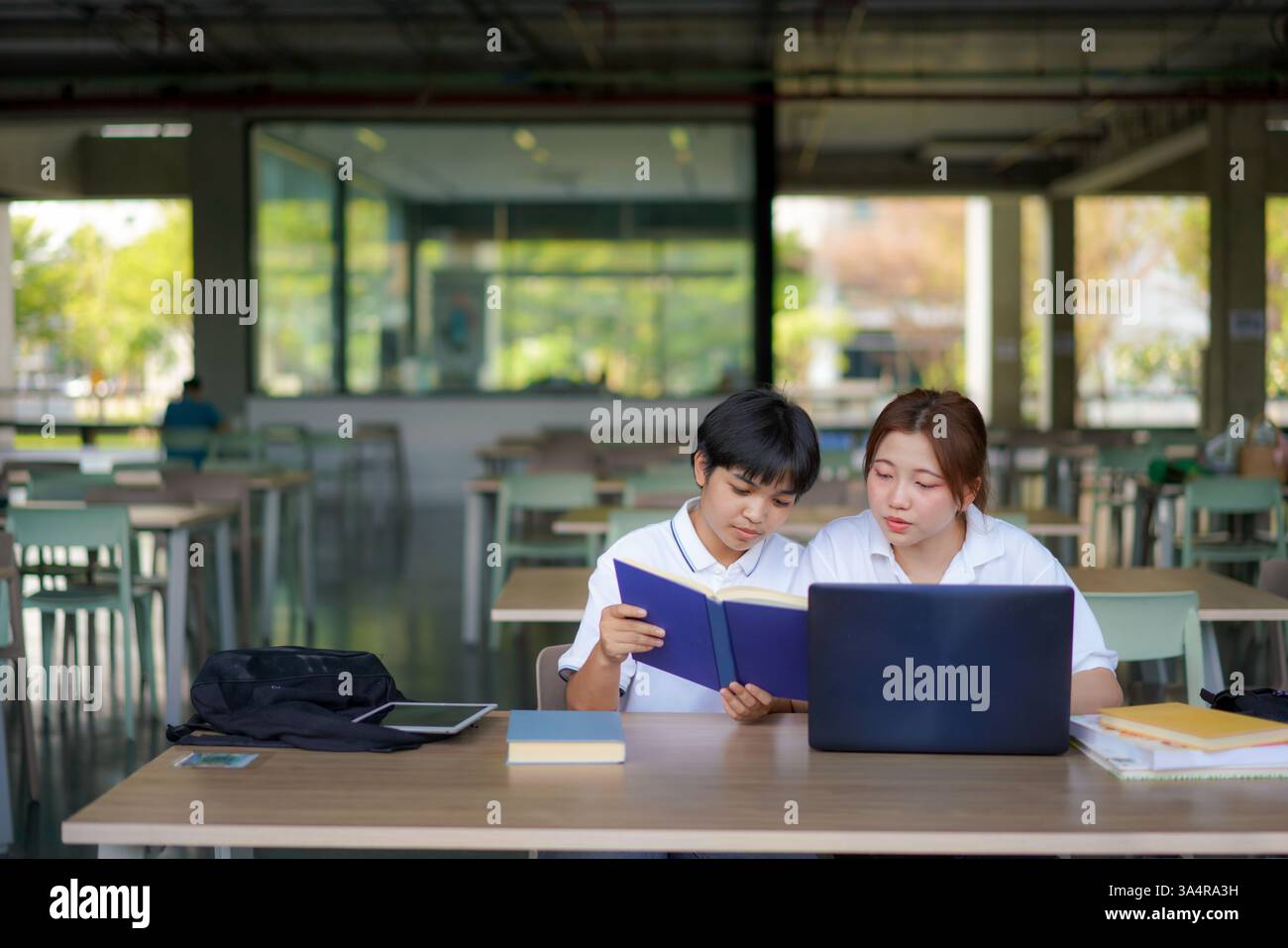 two asian students wearing school uniforms, actively discussing their ...