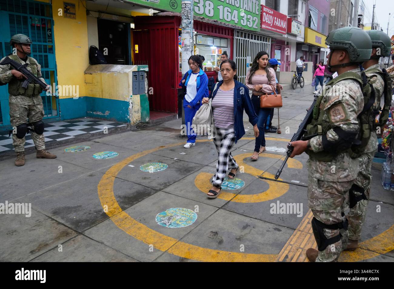 Pedestrians walk past soldiers in Lima, Peru, Wednesday, March 19, 2025 ...