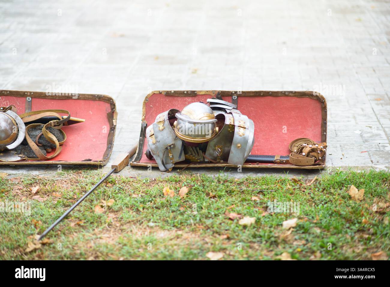 A display of Roman-style armor and red-painted shields laid out on the ...
