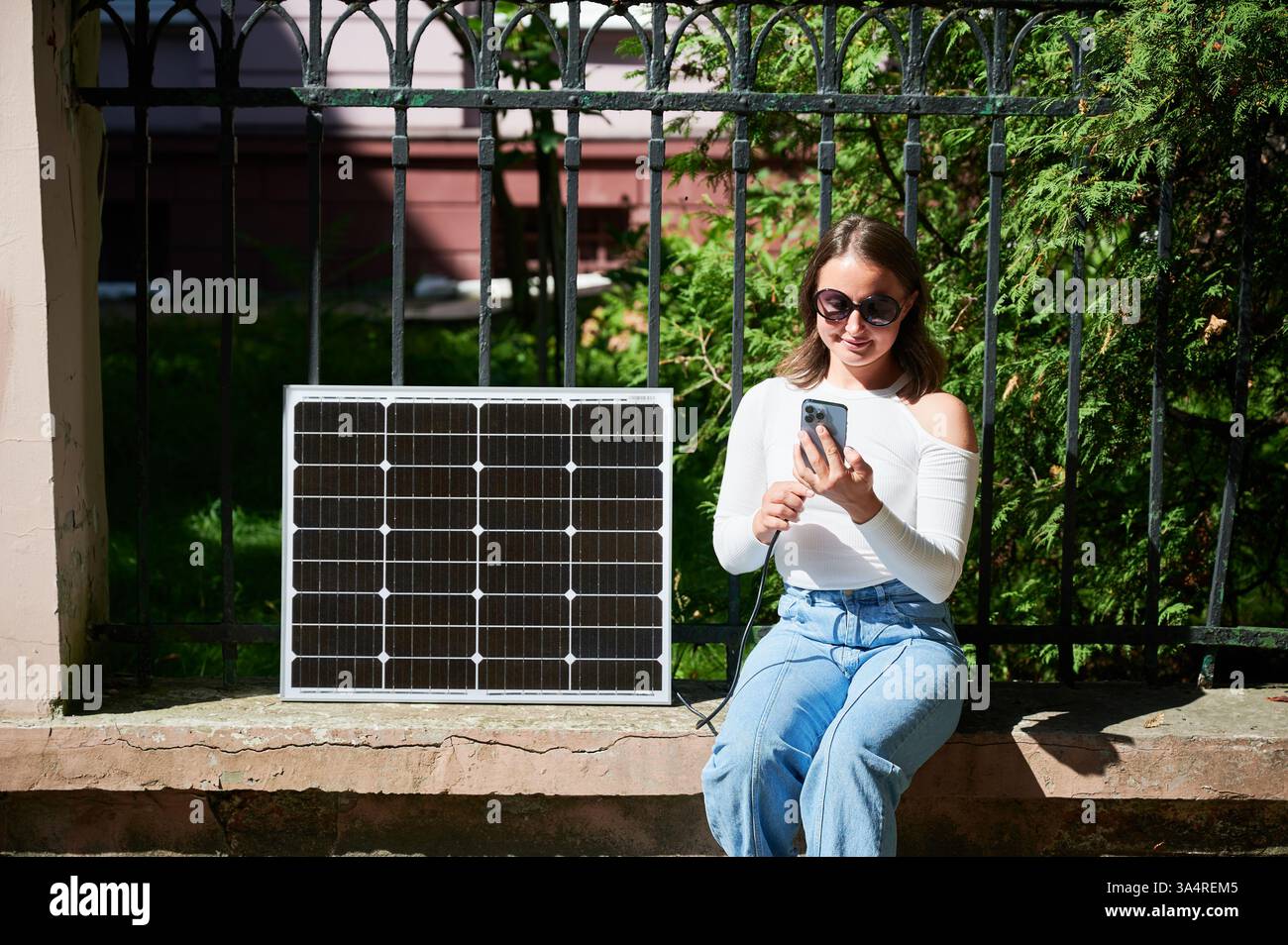 Happy woman connecting smartphone to photovoltaic solar panel ...