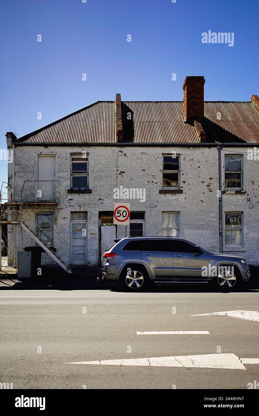 A serene street scene in Hobart, Tasmania: white brick wall, parked SUV ...