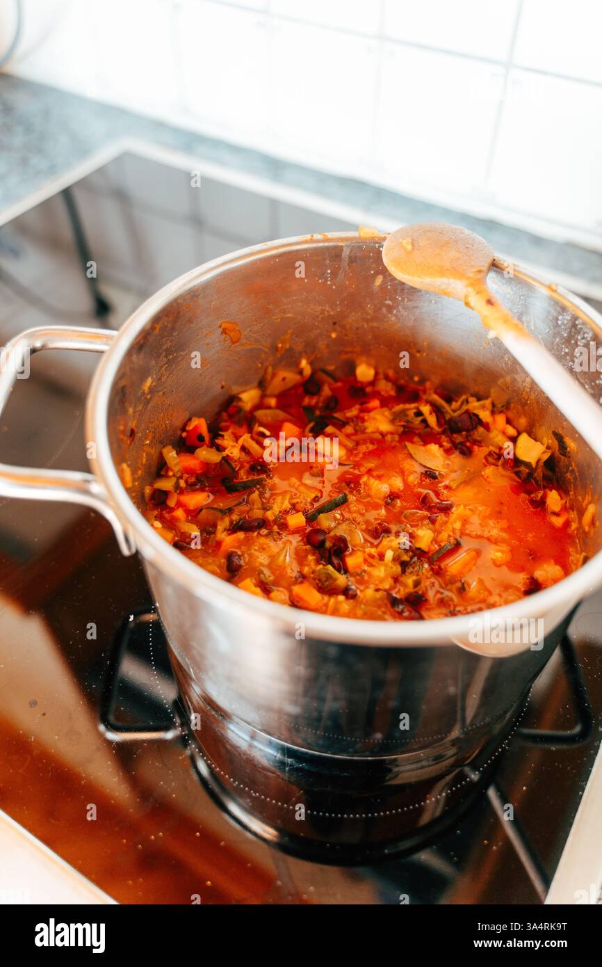 A pot filled with colorful vegetables simmers on the stove, releasing ...