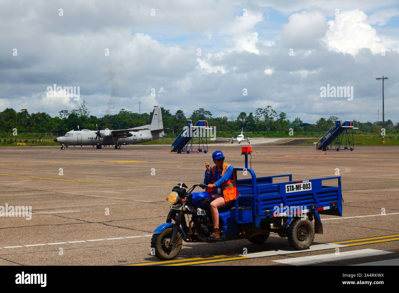 Female member of ground staff driving a blue auto rickshaw pickup ...