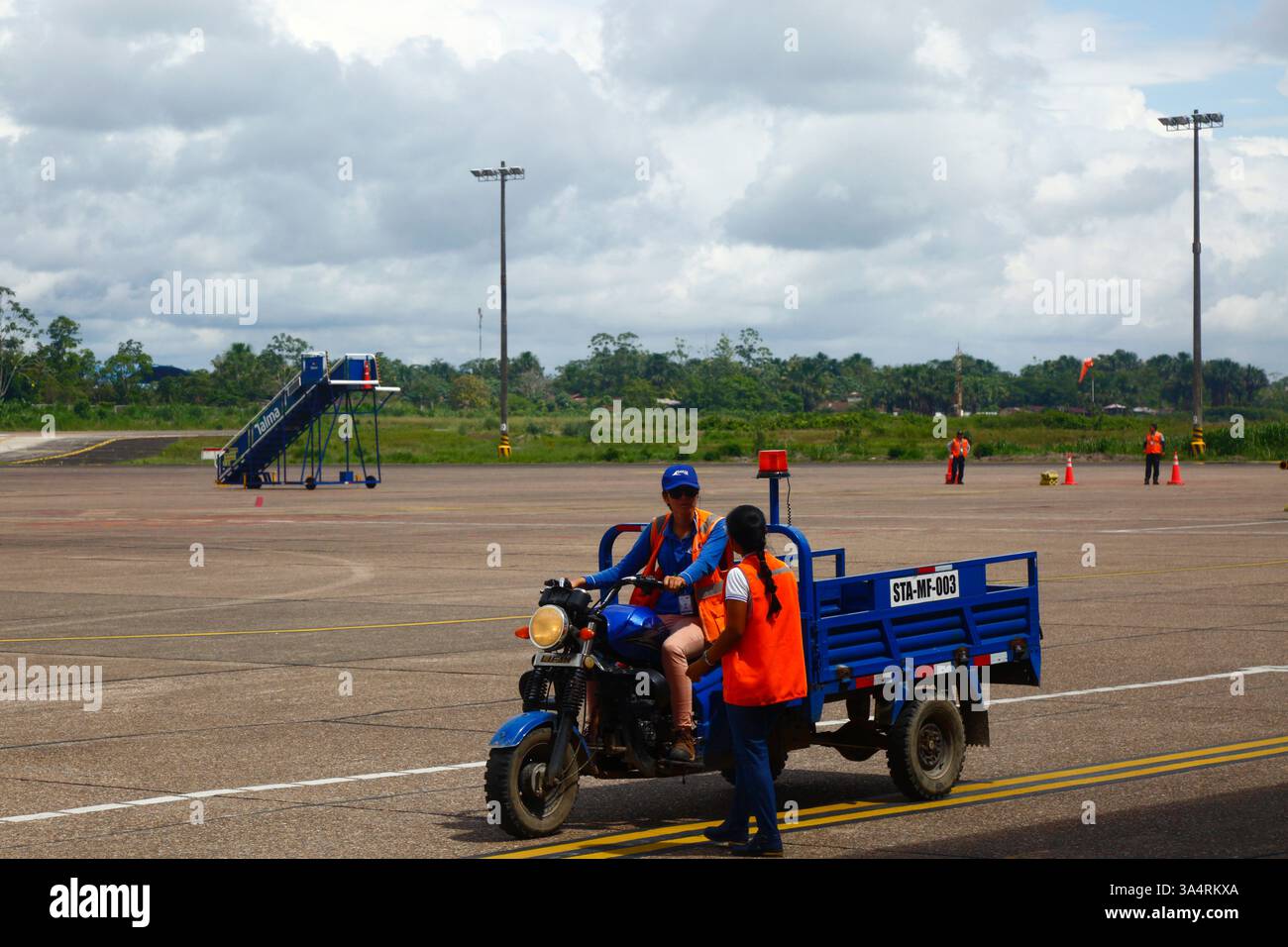 Female member of airport ground staff driving a blue auto rickshaw ...