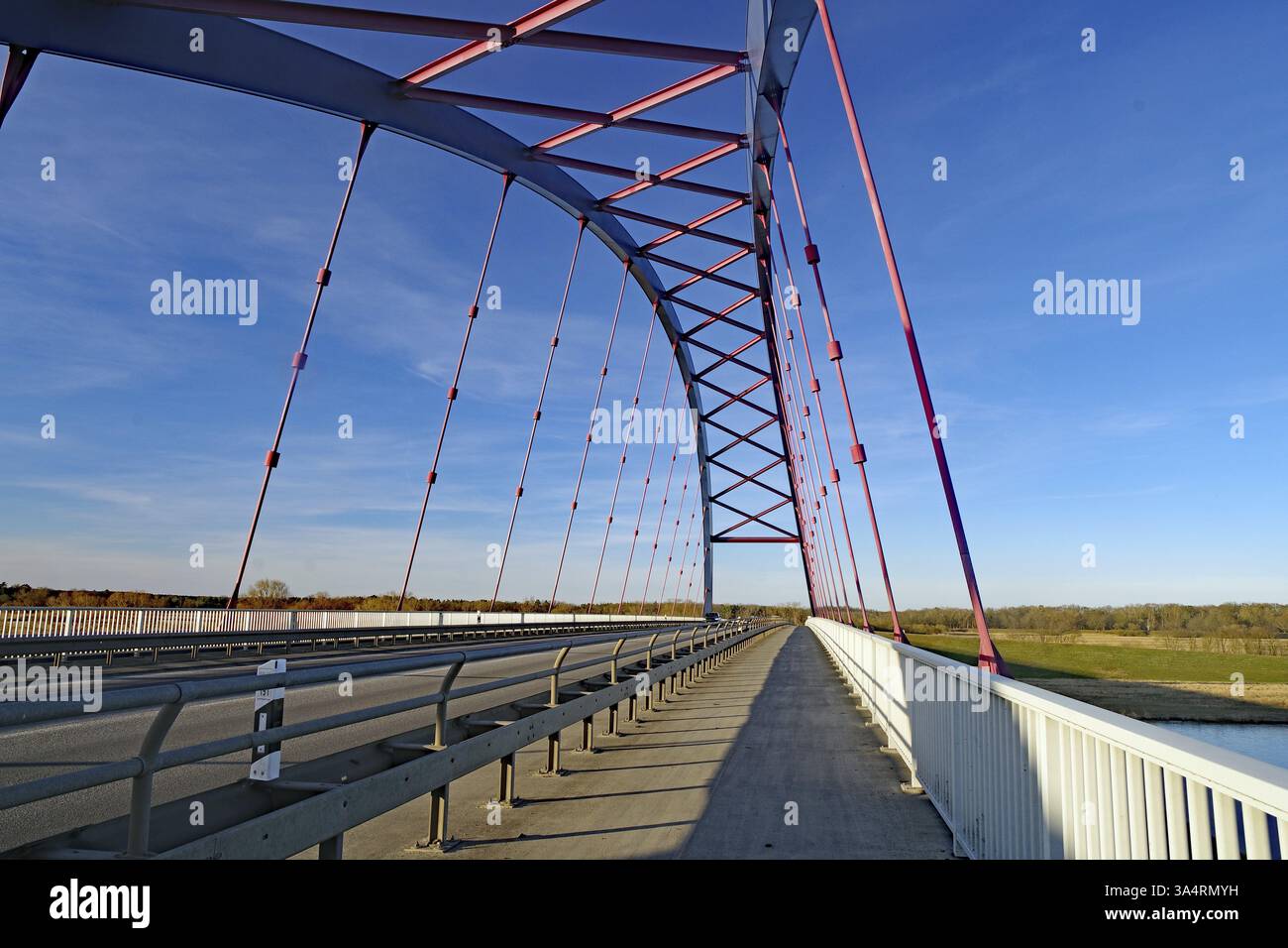 A modern steel bridge with pink and white struts spans a long distance ...
