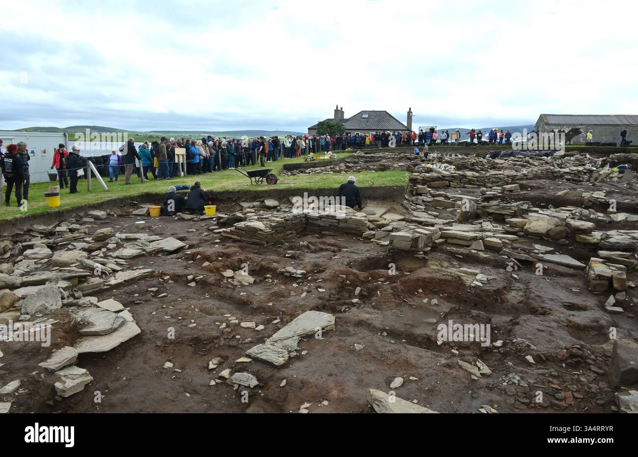 Tour group of visitors watching archeologists at work Ness of Brodgar ...