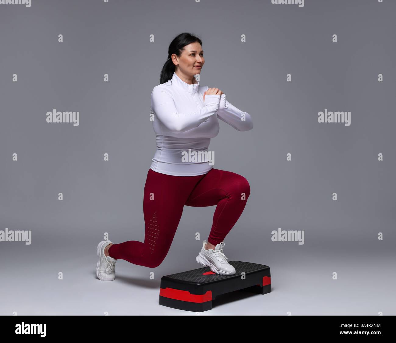 Plus size woman in gym clothes doing exercise with step platform on ...
