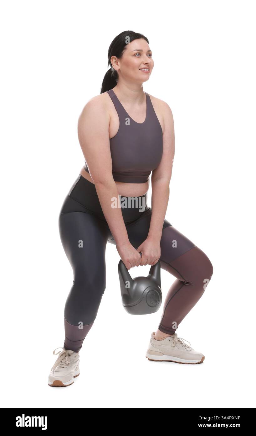 Plus size woman in gym clothes doing exercise with kettlebell on white ...