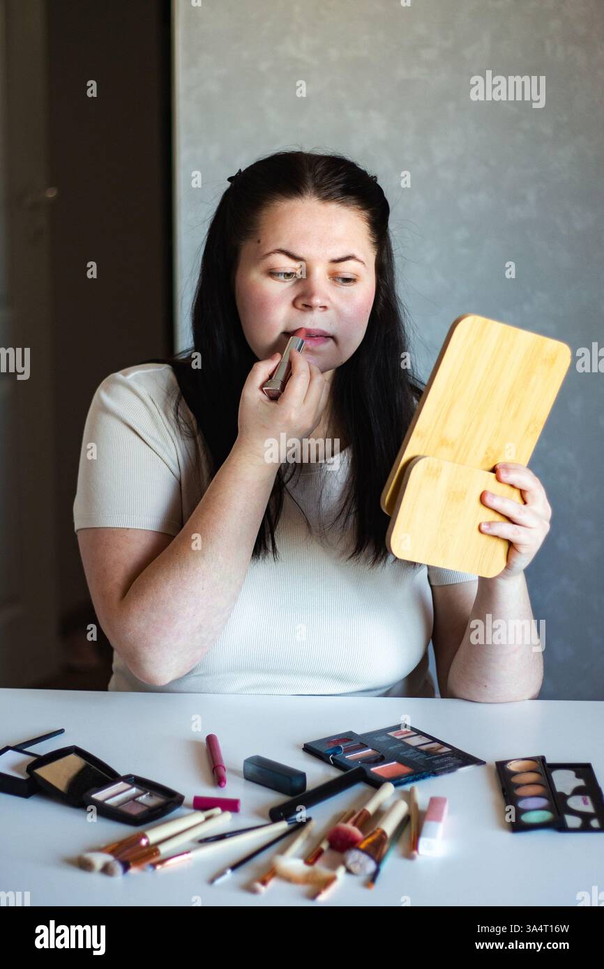 Vertical image of Millennial Caucasian woman doing self make up ...