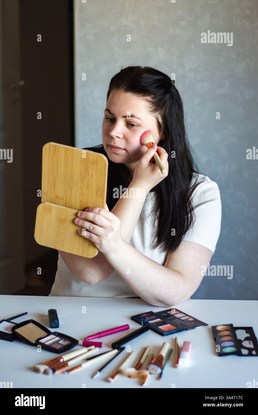 Vertical image of Millennial Caucasian woman doing self make up ...