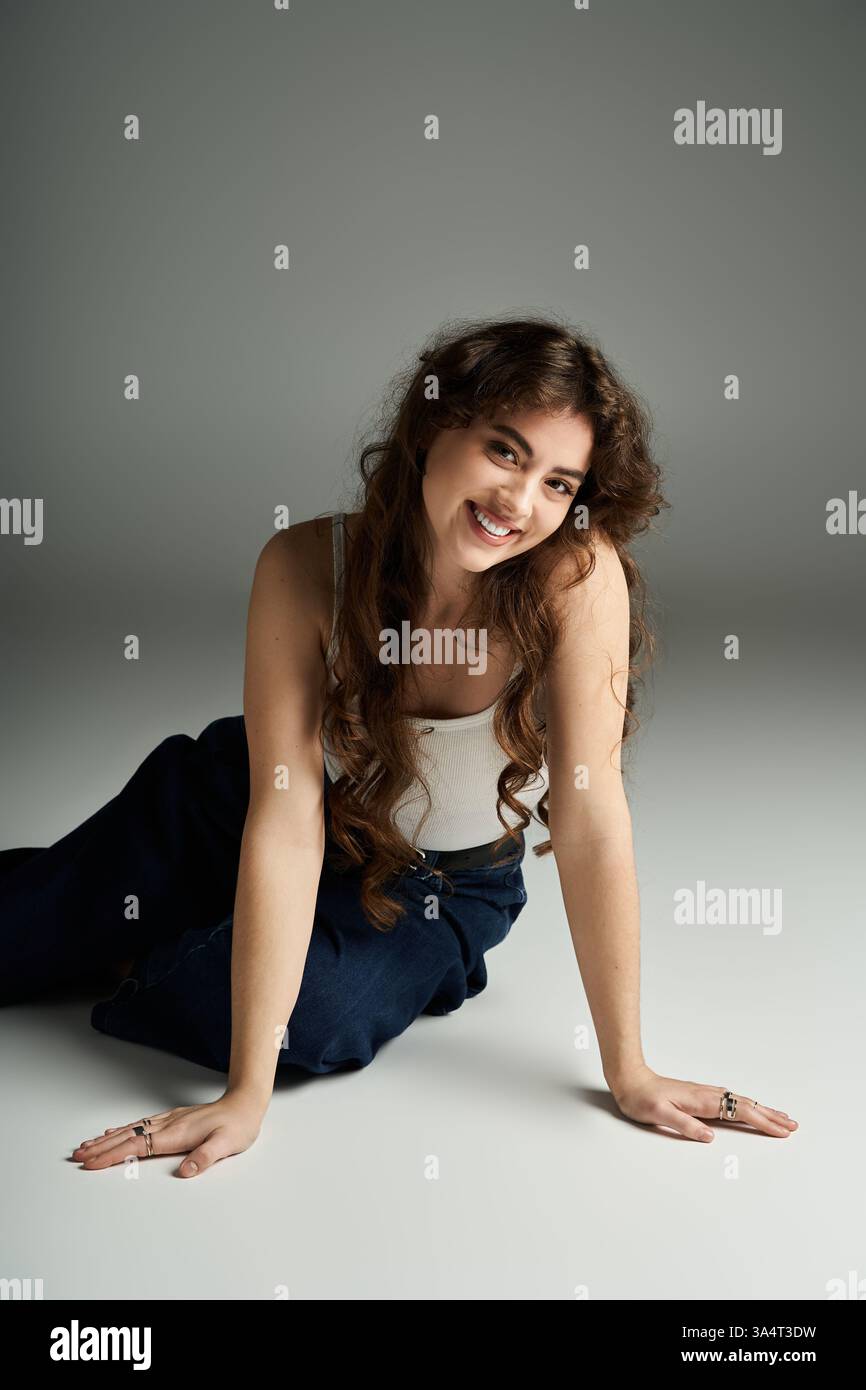Charming young woman wearing a trendy outfit poses playfully, radiating ...