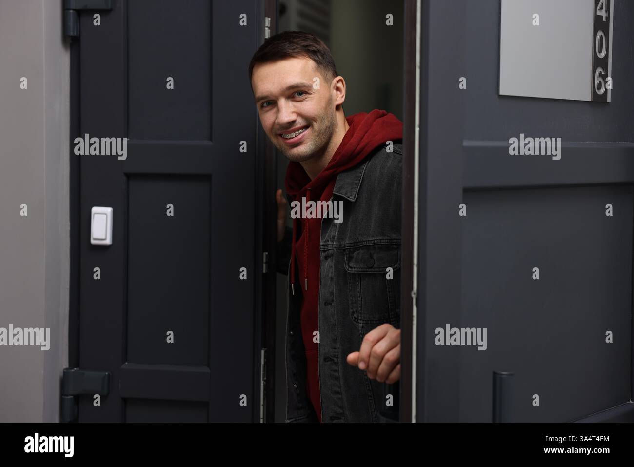Cheerful man meeting guests in doorway of his apartment Stock Photo - Alamy
