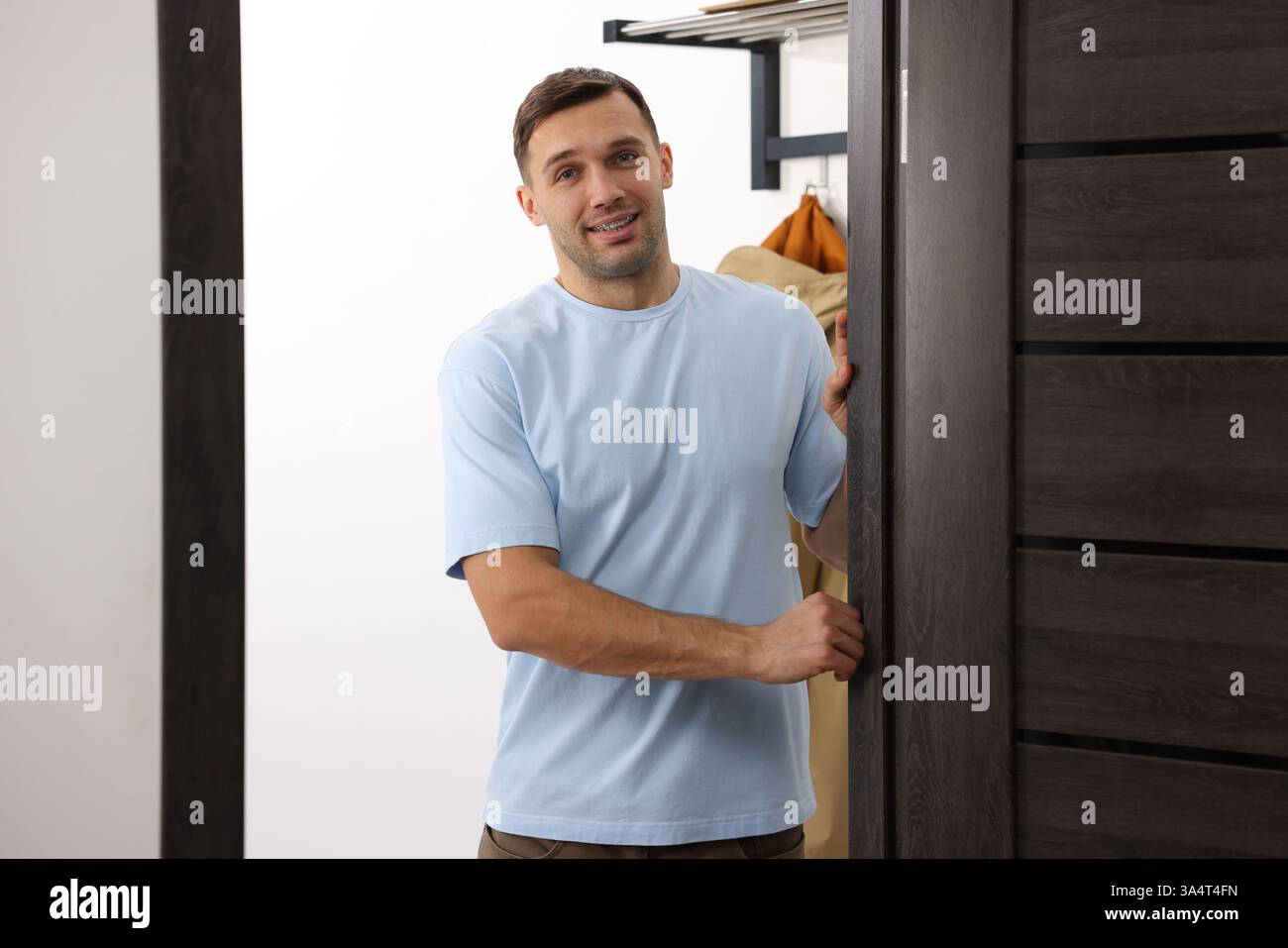 Cheerful man welcoming guests to his apartment Stock Photo - Alamy