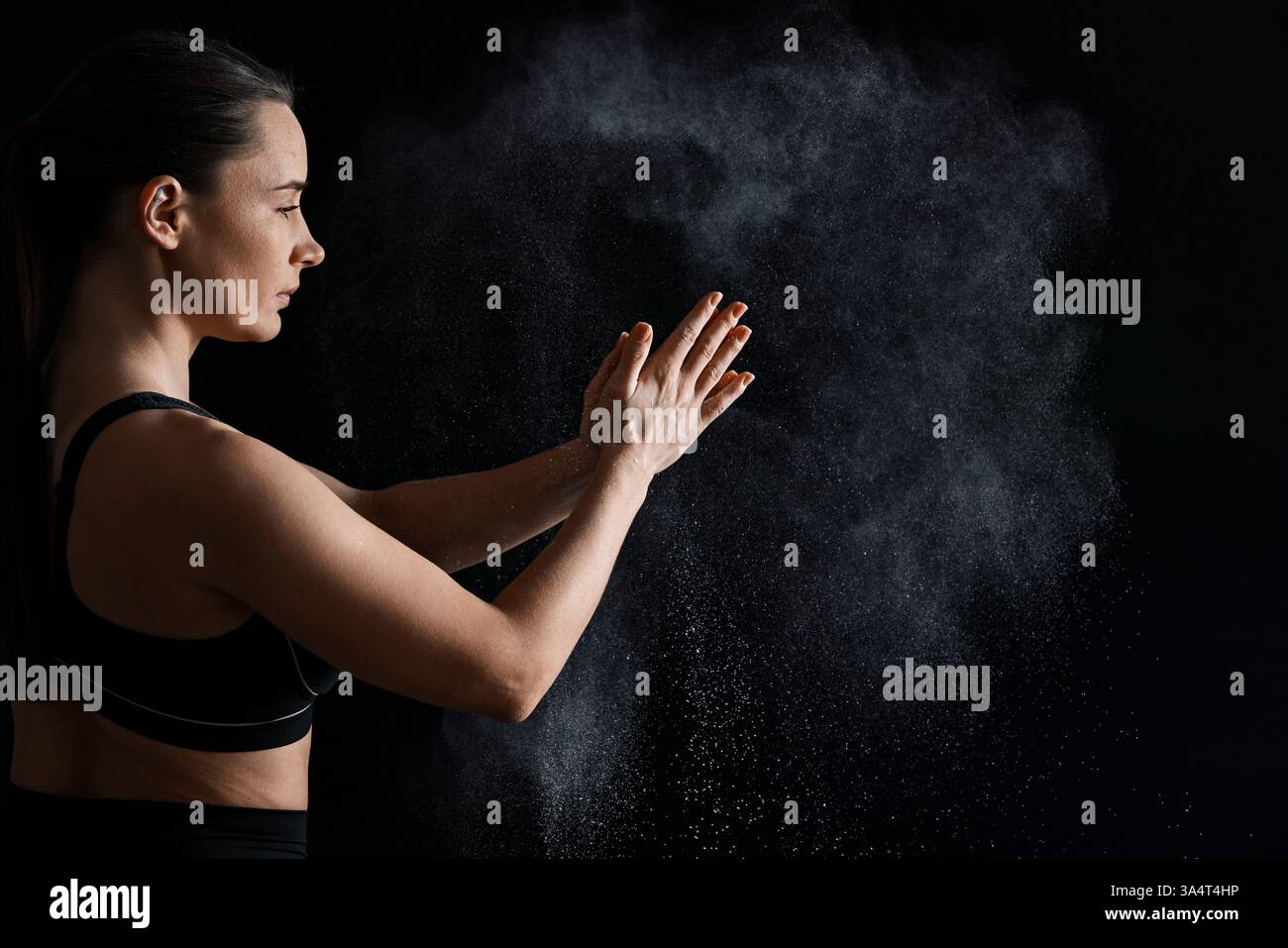 Woman clapping hands with talcum powder before training on black ...