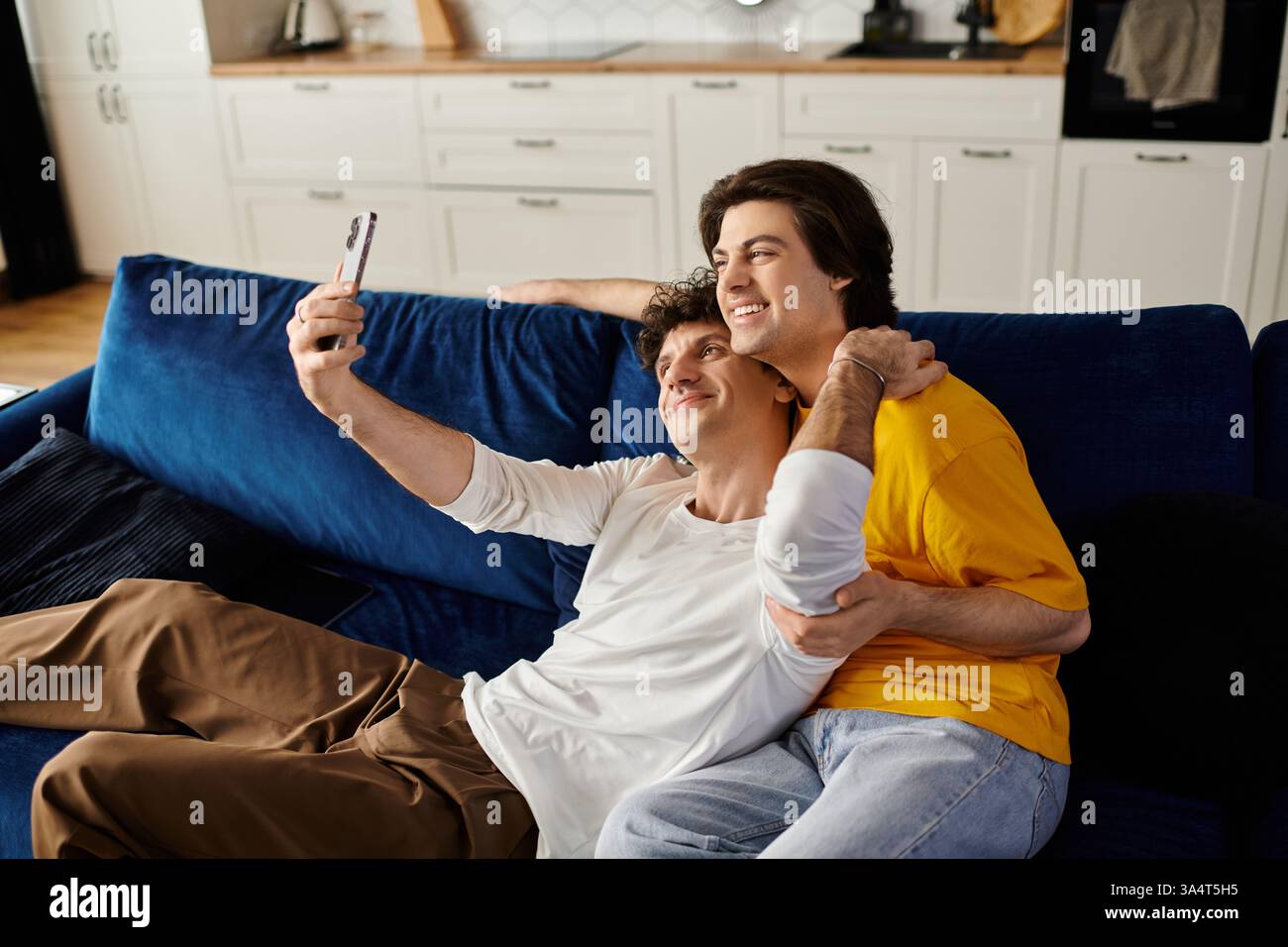 Two good looking men embrace joyfully while taking a selfie together in ...
