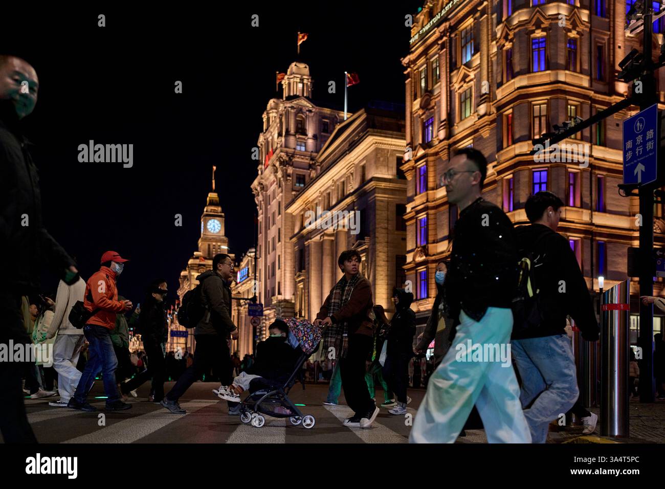 Visitors walk across a street as they tour the Shanghai Bund, in ...