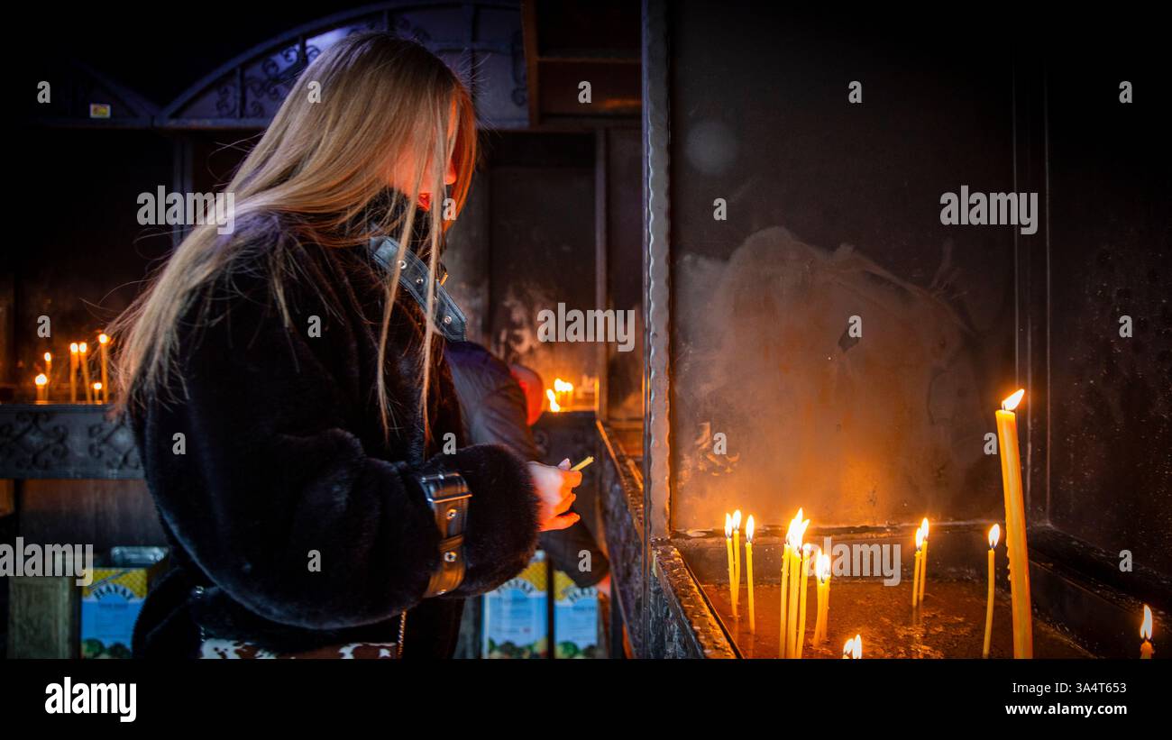 A woman lights a candle and prays during a mass prayer for the victims ...