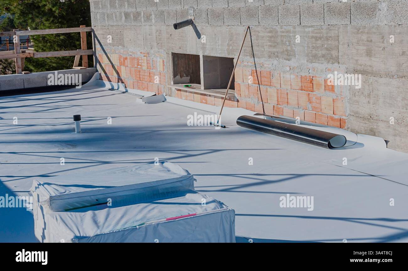 Construction site with a flat roof being waterproofed. The image shows a partially installed ...