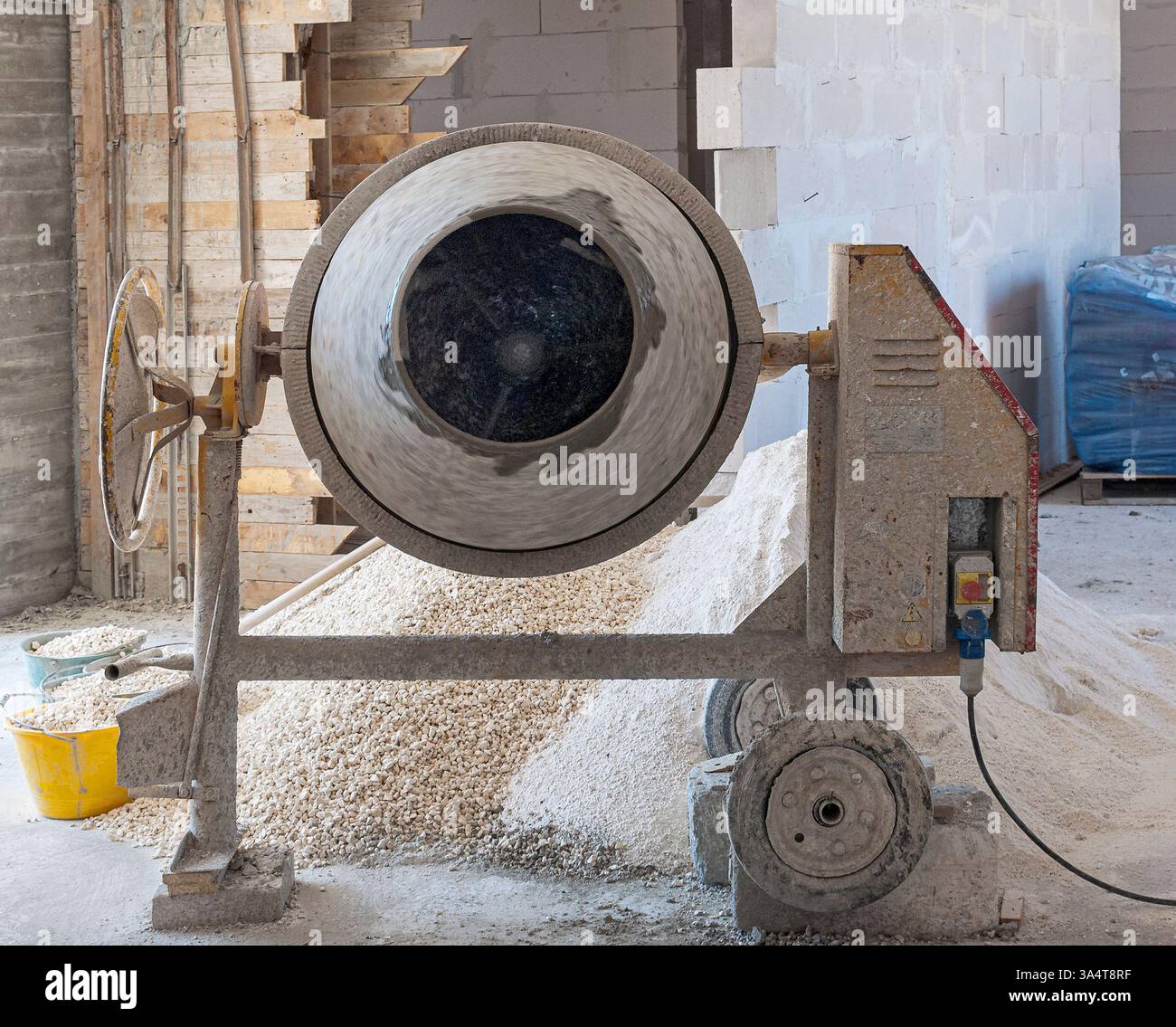 concrete mixer installed on the construction site next to a pile of ...