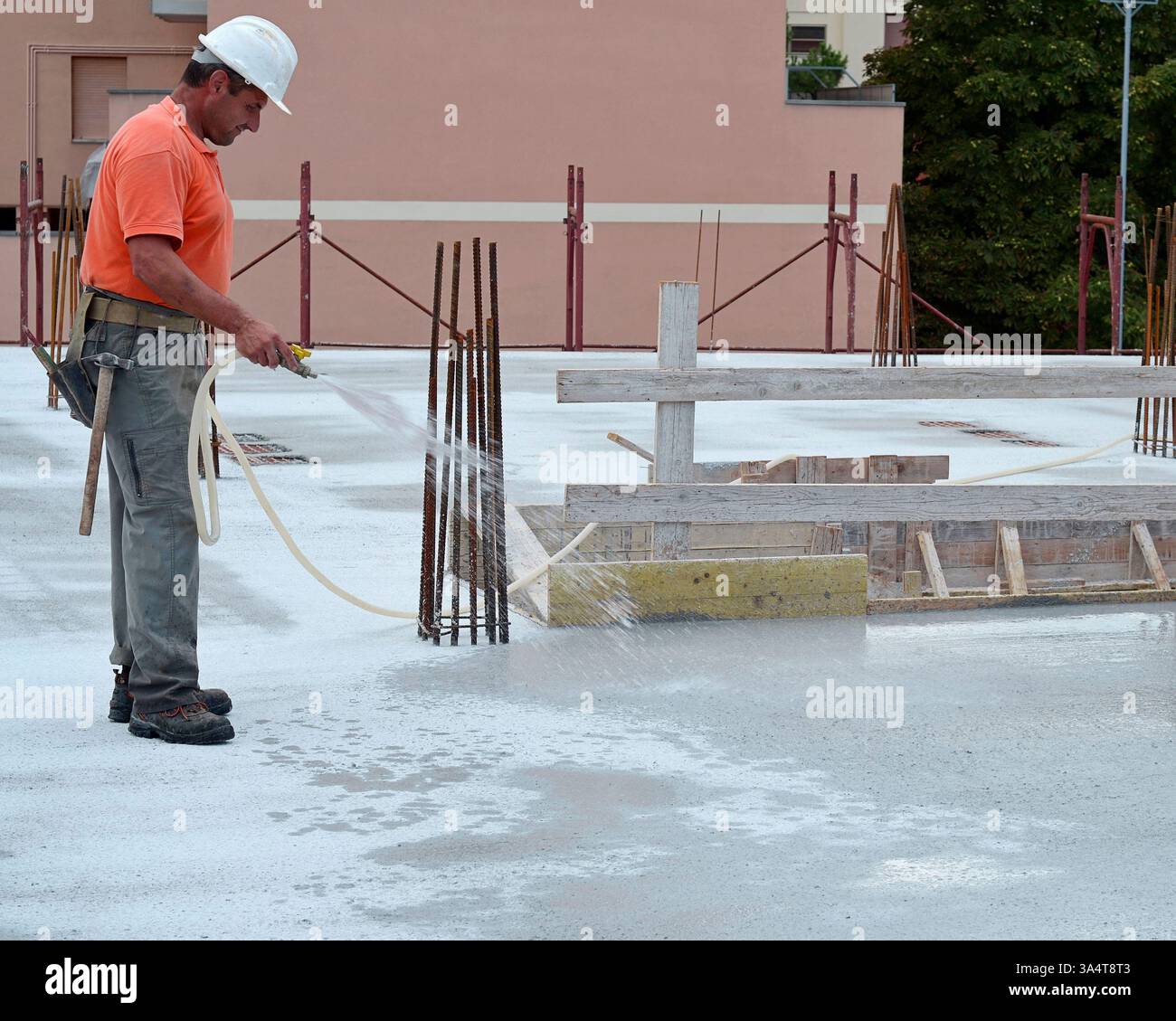 Construction carpenter waters the surface of a reinforced concrete ...