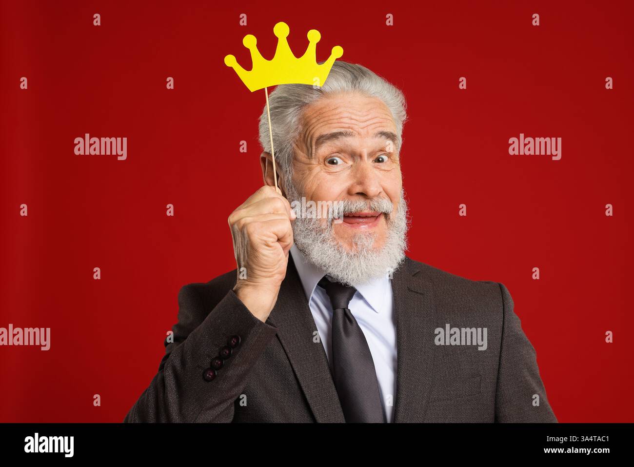 Senior man holding stick with paper crown on red background Stock Photo ...