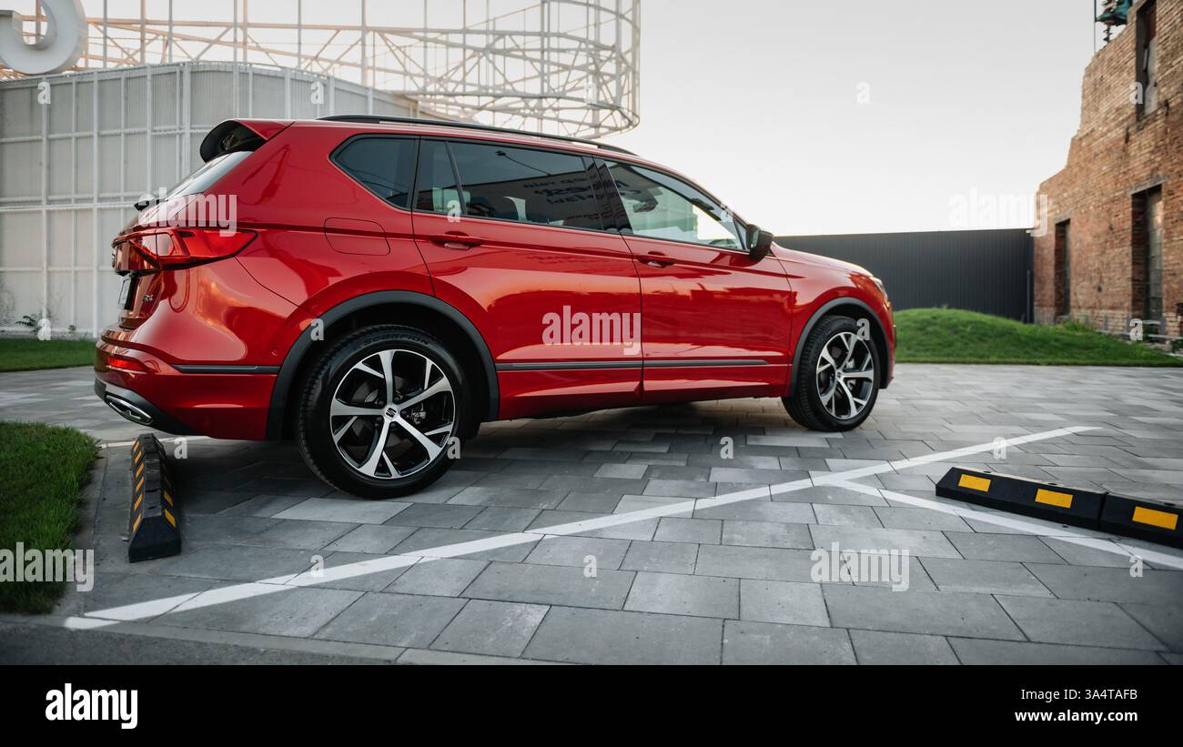 Red SEAT Tarraco in parking lot at sunset. Rear side view of family SUV ...