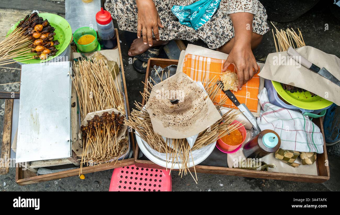 Street vendor preparing chicken satay at a traditional food stall in ...