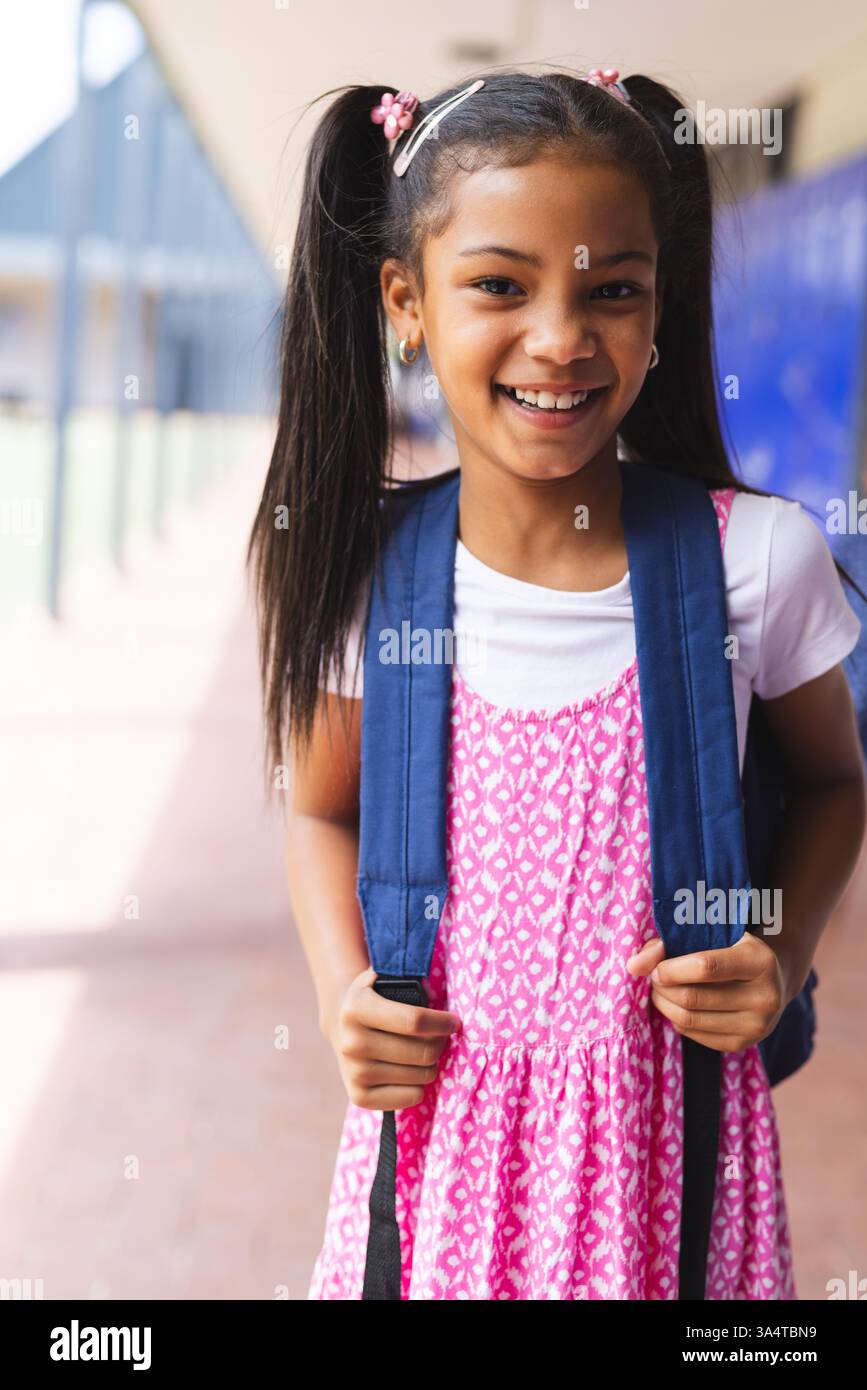 Smiling girl with backpack standing in school hallway, ready for class ...