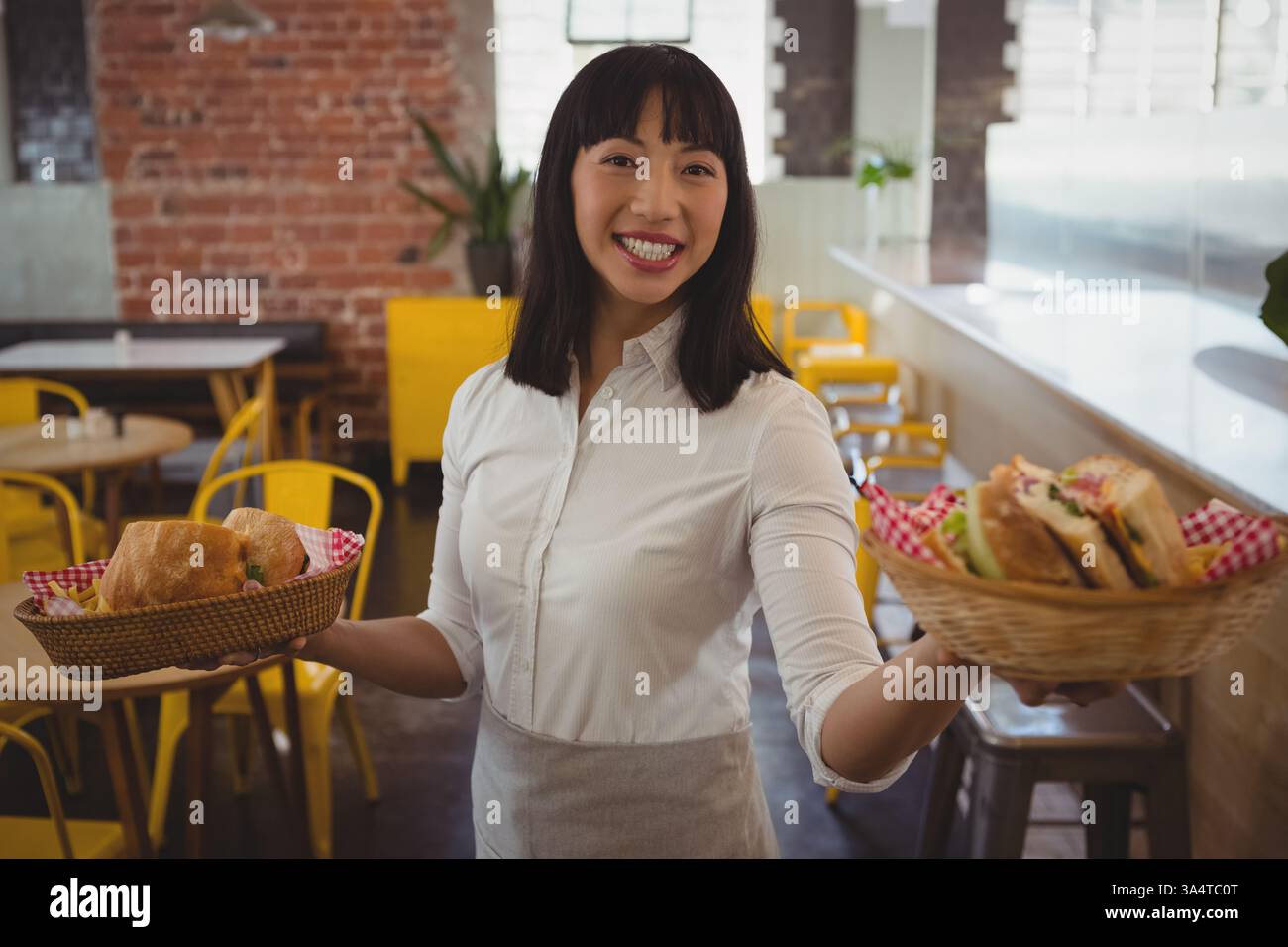Smiling waitress serving sandwiches in cozy cafe with brick wall and ...