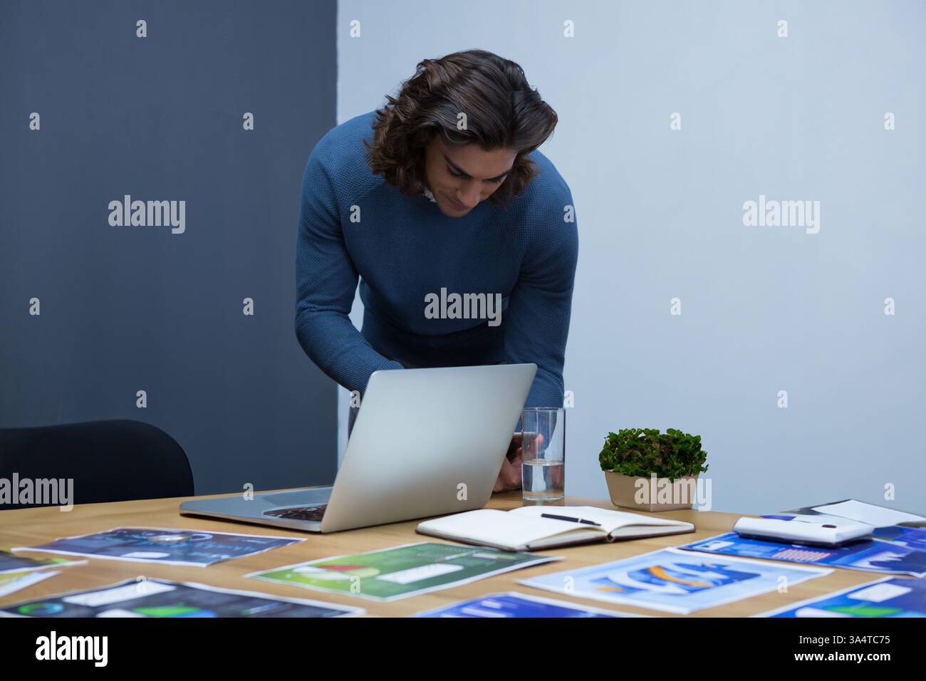 Businessman reviewing documents on laptop at office desk with focus ...