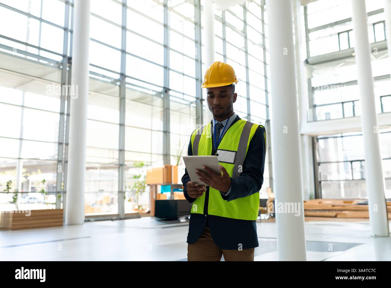 Engineer in safety vest and hard hat using tablet in modern building ...