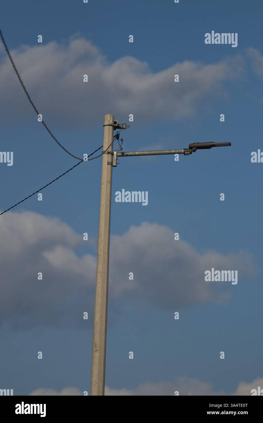 A wooden utility pole stands tall with a streetlight attached ...
