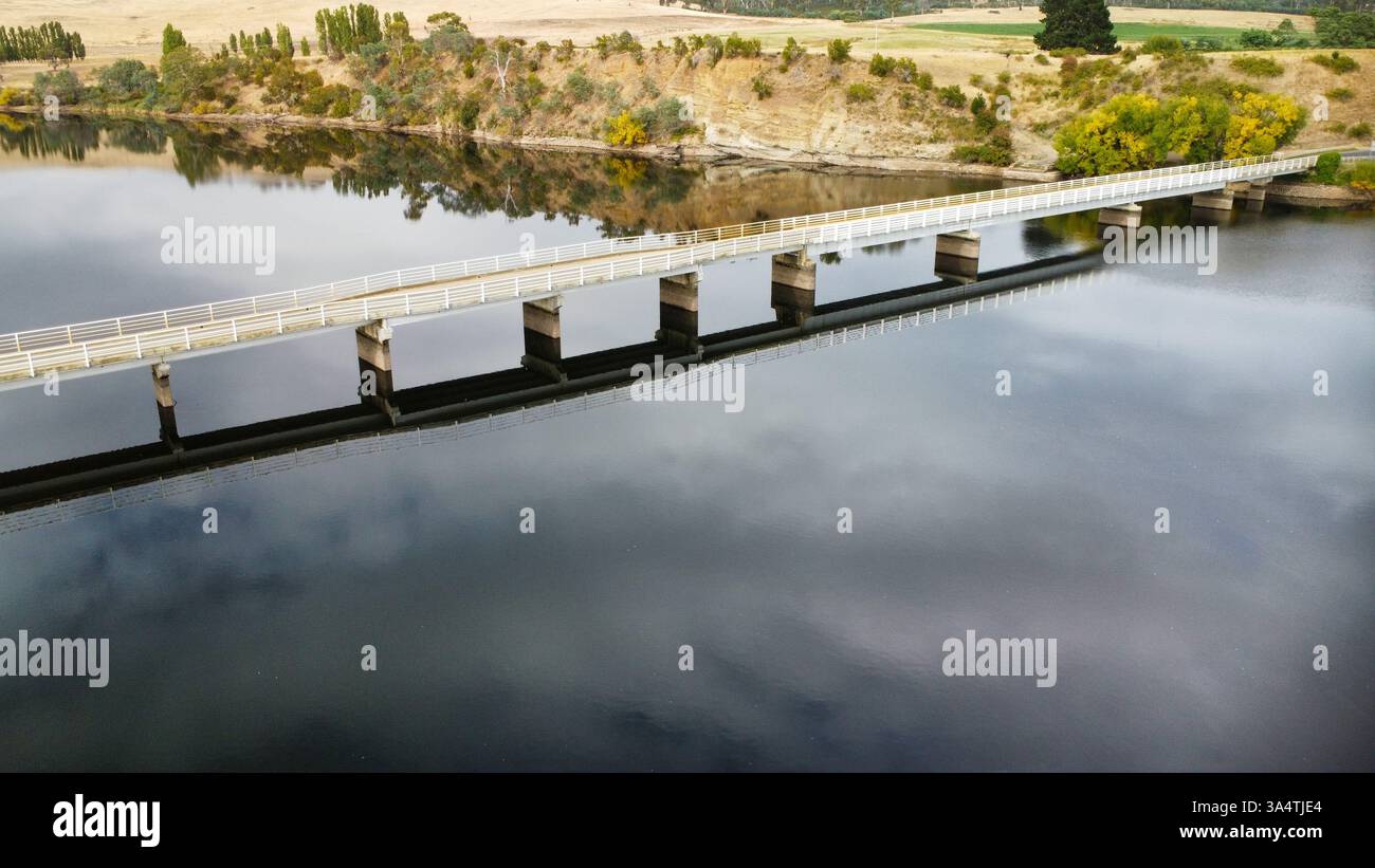 A long bridge over a shallow and calm dark lake on a cloudy day, seen ...