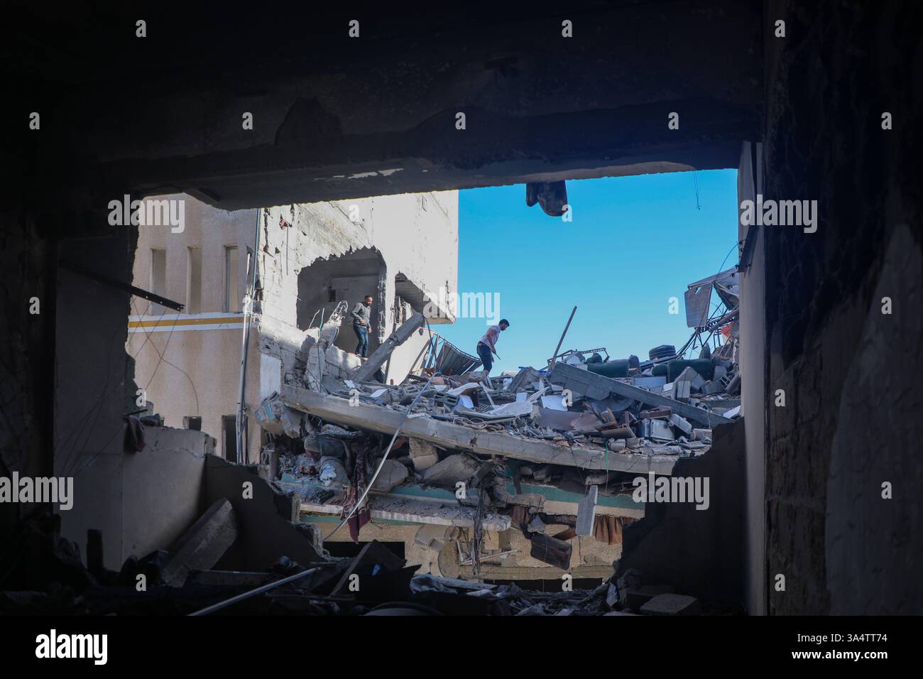 Gaza. 19th Mar, 2025. People are seen among the rubble of a house ...