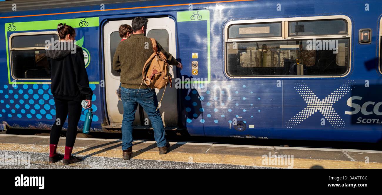 A family about to board a ScotRail commuter train in Carluke, Scotland ...