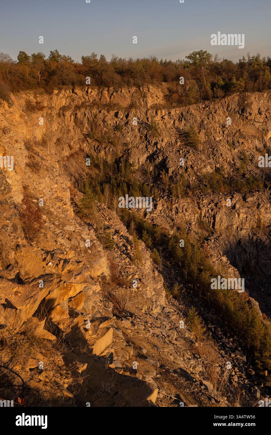 Rocky cliff with rough textures, golden sunlight, and sparse vegetation ...