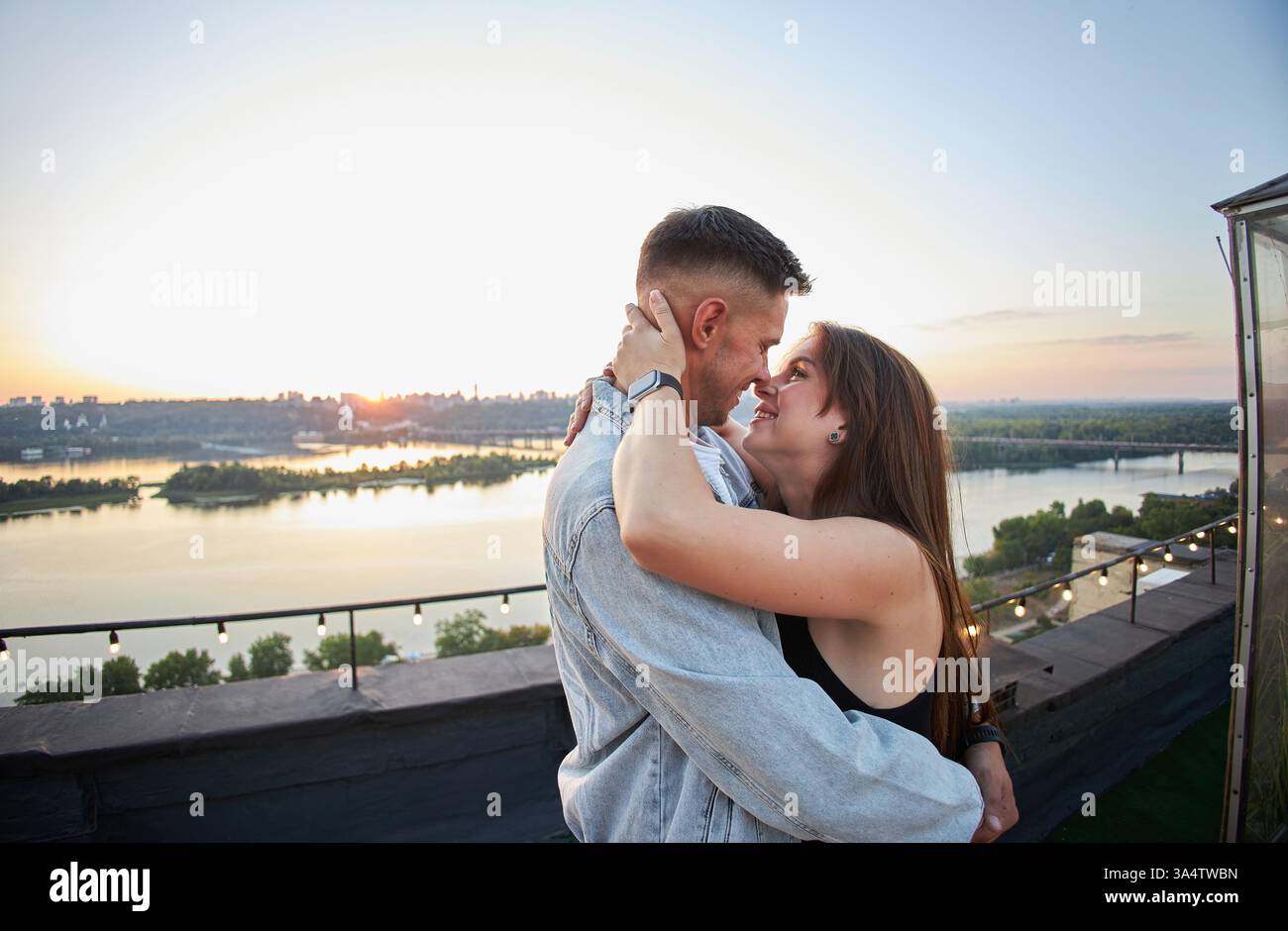 A young couple kisses and embraces during a romantic rooftop date, with ...