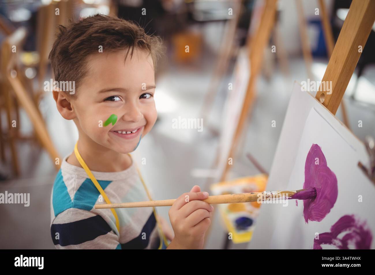 Smiling boy painting on easel in school art class, enjoying creativity ...